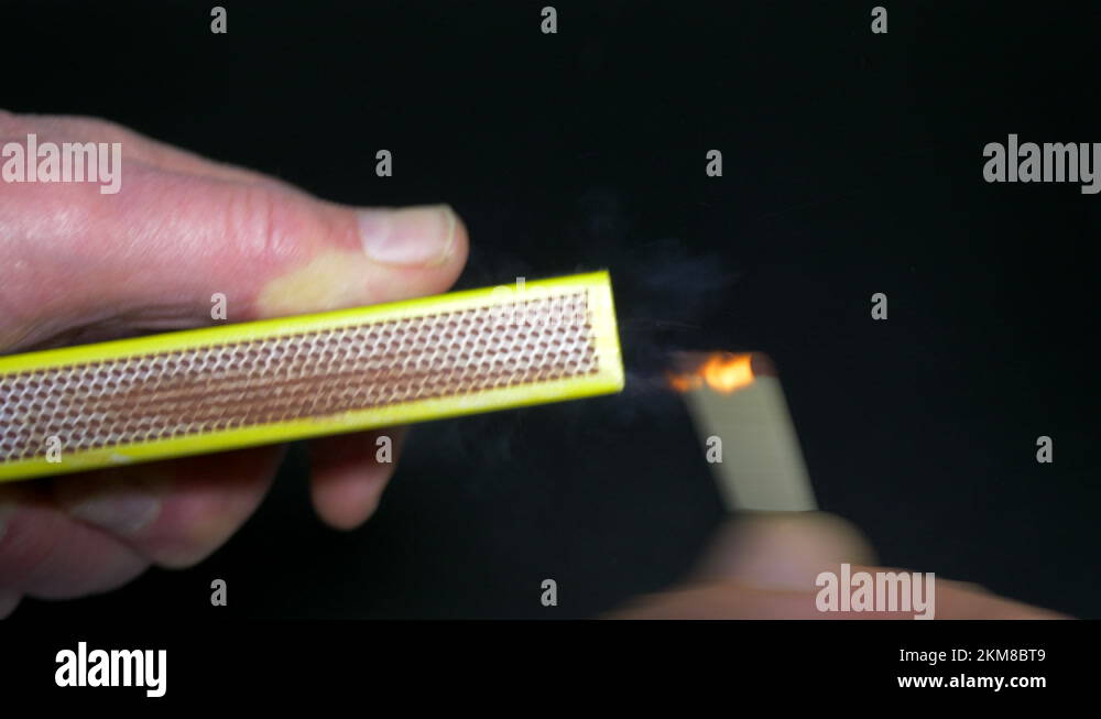 Man's hand striking a match alight on the side of a matchbox Stock ...