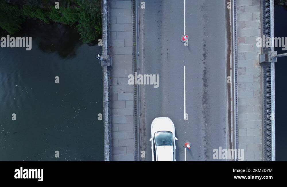Side ways moving aerial over a road bridge above deep water, traffic is ...