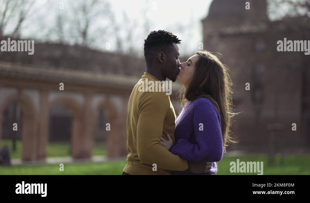 Black man kissing white girlfriend standing outside at park Stock Video ...