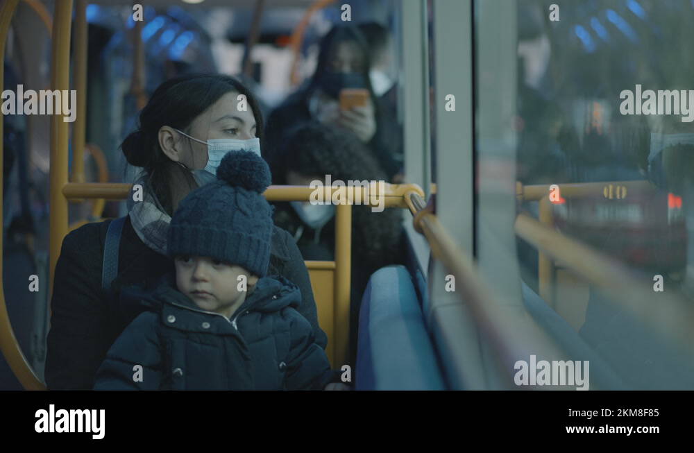 Parent and child riding bus during pandemic wearing covid-19 face mask ...