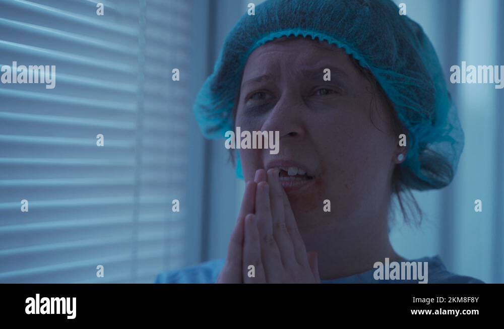 Stressed woman with facial injuries crying and praying in hospital ...