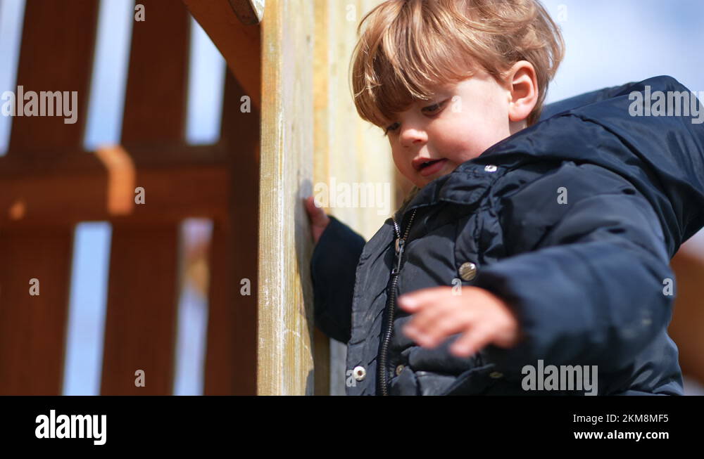 Distracted child hitting head at playground park. Young boy hits ...