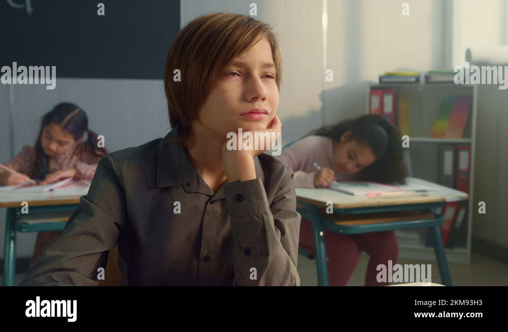 Boy studying in classroom with classmates. Male student boring during ...