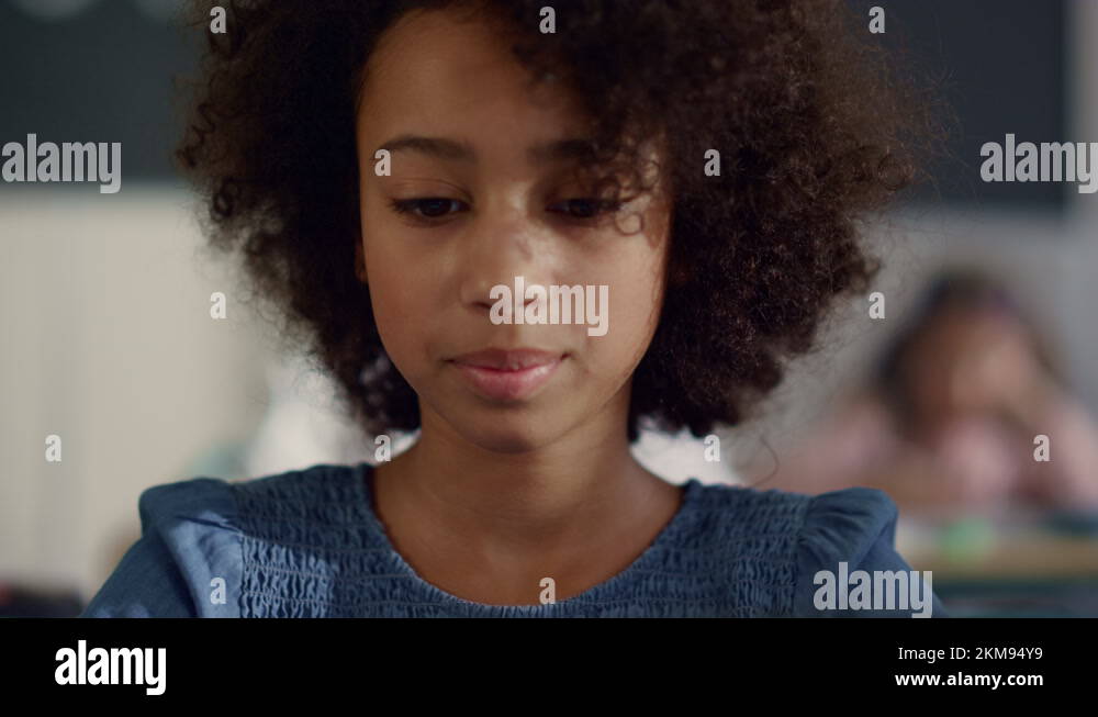 Girl sitting at desk in classroom. Pensive student learning at ...