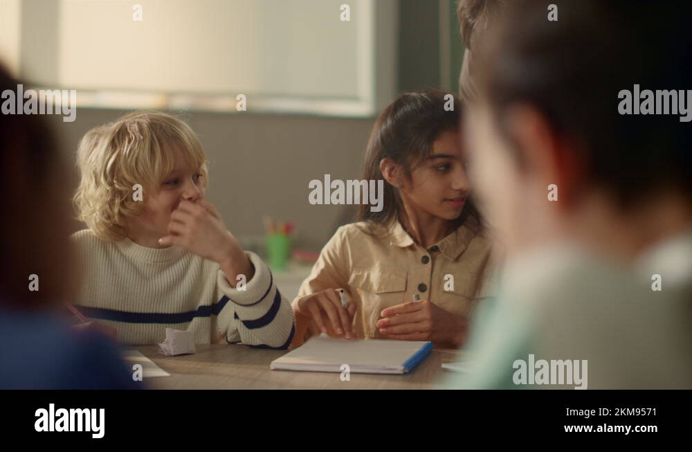 Teacher talking with students at round table in classroom. Pupils ...