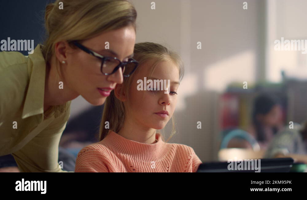 Girl using digital tablet. Teacher helping student to do class work on ...