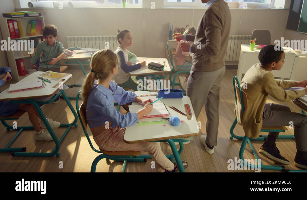 Teacher explaining lesson to students in classroom. Smart kids having ...