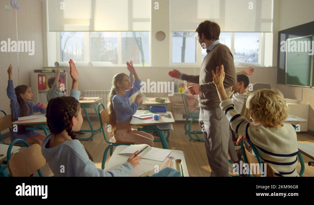 Pupils learning in classroom. Male teacher asking questions at lesson ...