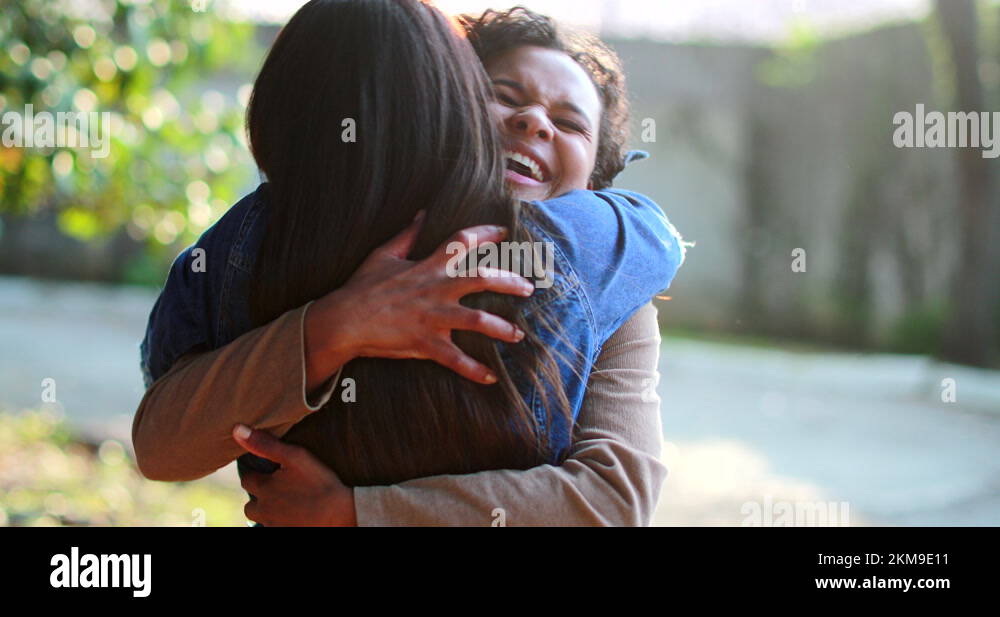 Two friends reunion meeting embrace and hug, outside in sunlight park ...