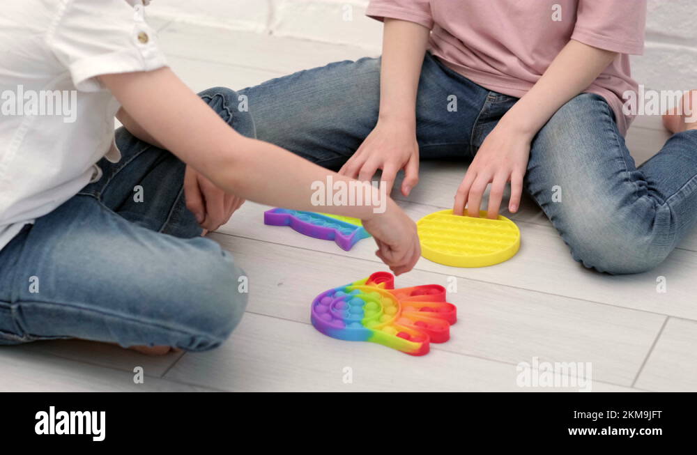 Kids playing with pop it sensory toy. boy and girl pressing on colorful ...