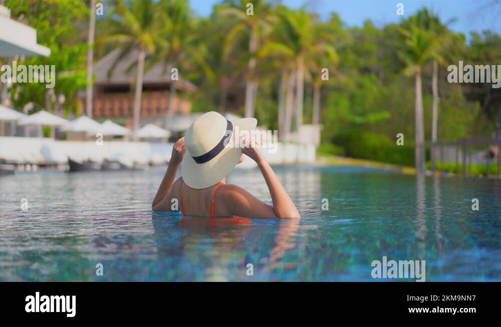 Back view of a female tourist standing half submerged in a swimming ...