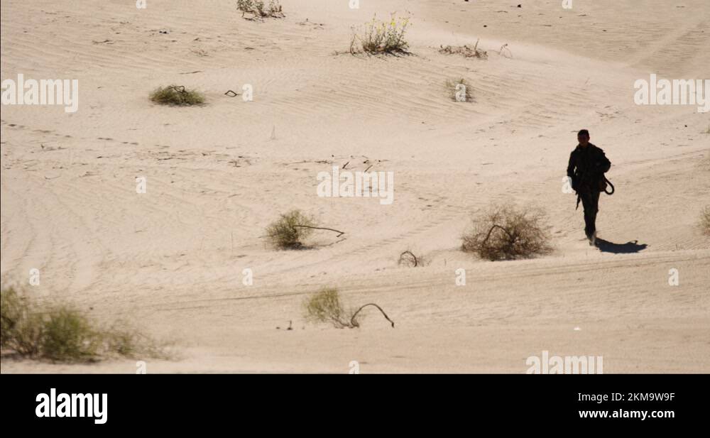 Silhouetted soldier wandering in slow motion in hot desert alone and ...