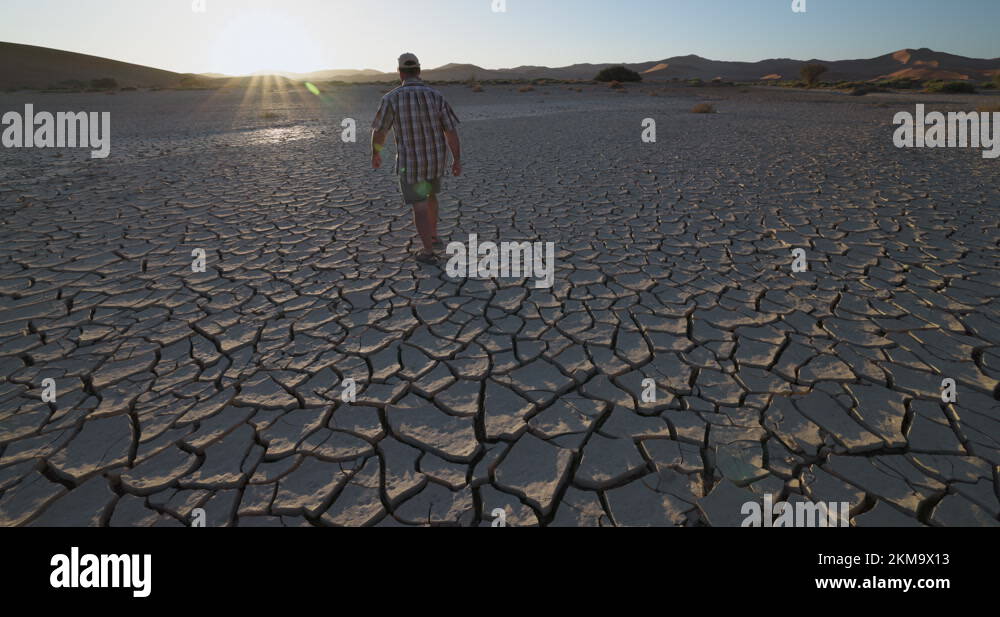 Climate change.Devastated farmer walking across dry dam due to drought ...