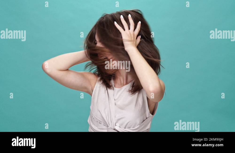 Angry screaming brunette woman moving her head in the blue studio Stock ...