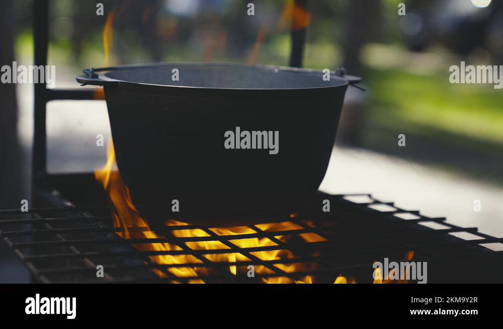 Cooking pot stands on a grate with a large flame of fire, cooking ...