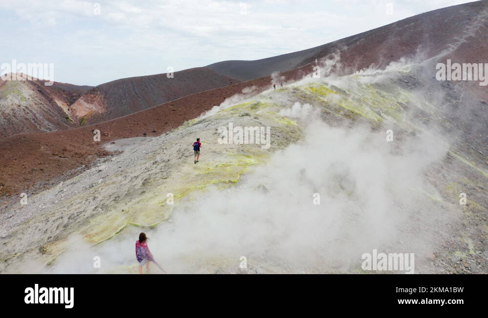 Male and female hikers trekking on volcano, walking trough sulfuric ...