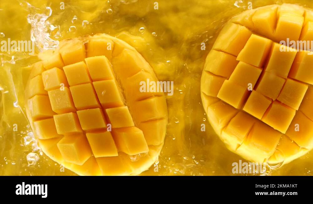 Mango falling and splashing into water on a yellow background, slow ...