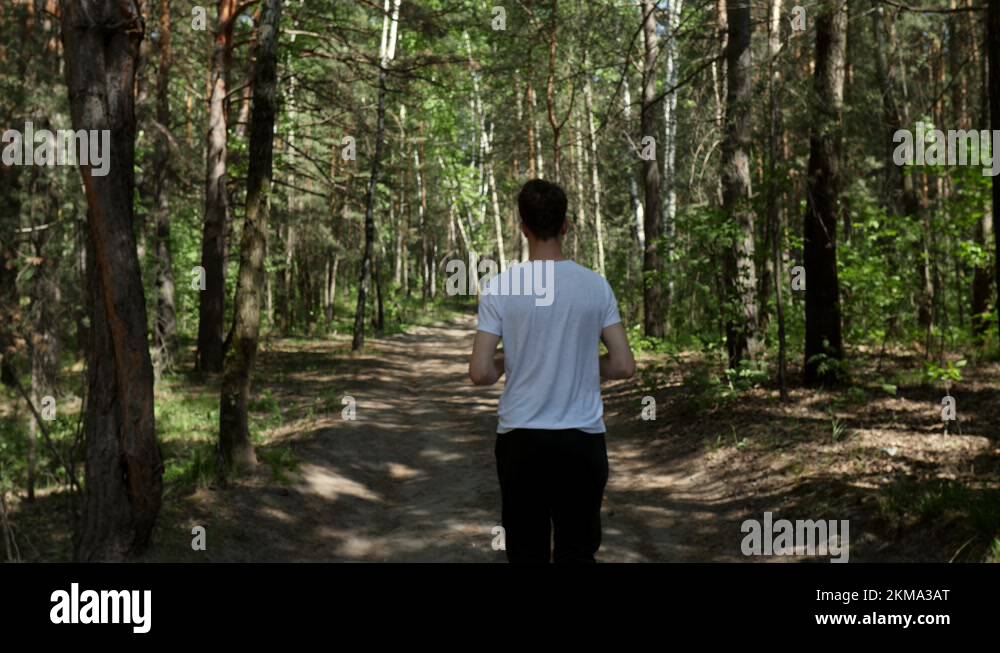 Young man running in the park from behind side view of healthy ...