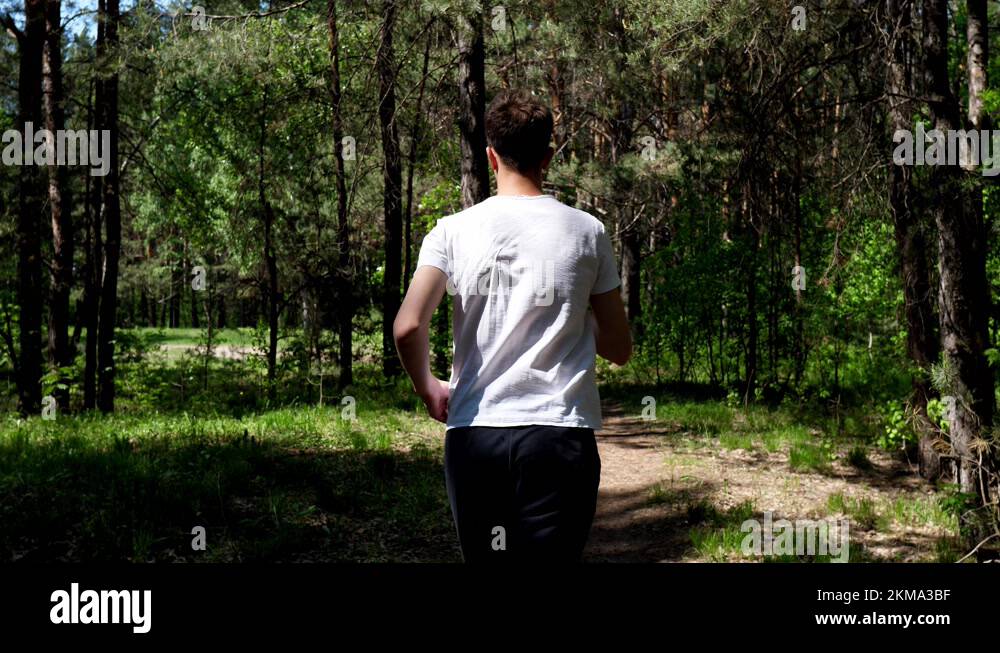 Young man running in the park from behind side view of healthy ...