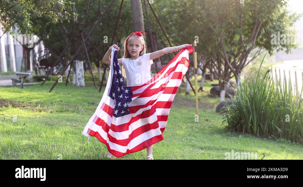 4k. Kid waving national USA flag outdoors. Cute Little Girl seven years ...