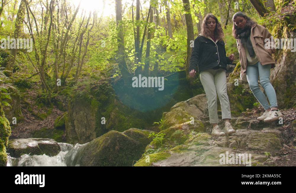 Young girls take a tour through green forest with waterfall in the ...