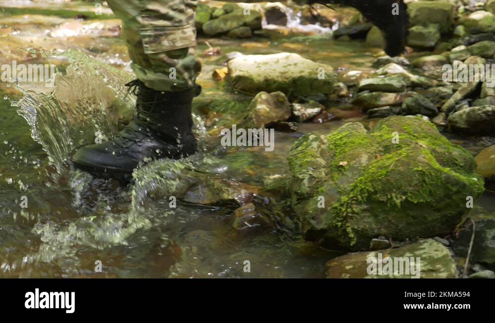 close-up . feet in ankle boots step into a mountain stream, passing it ...