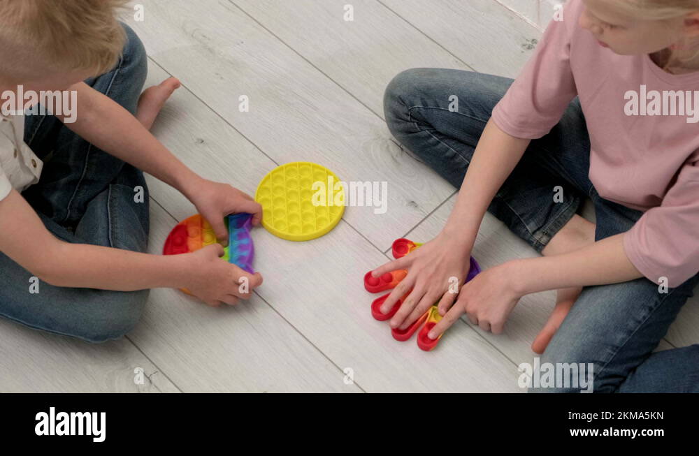 Kids playing with pop it sensory toy. boy and girl pressing on colorful ...