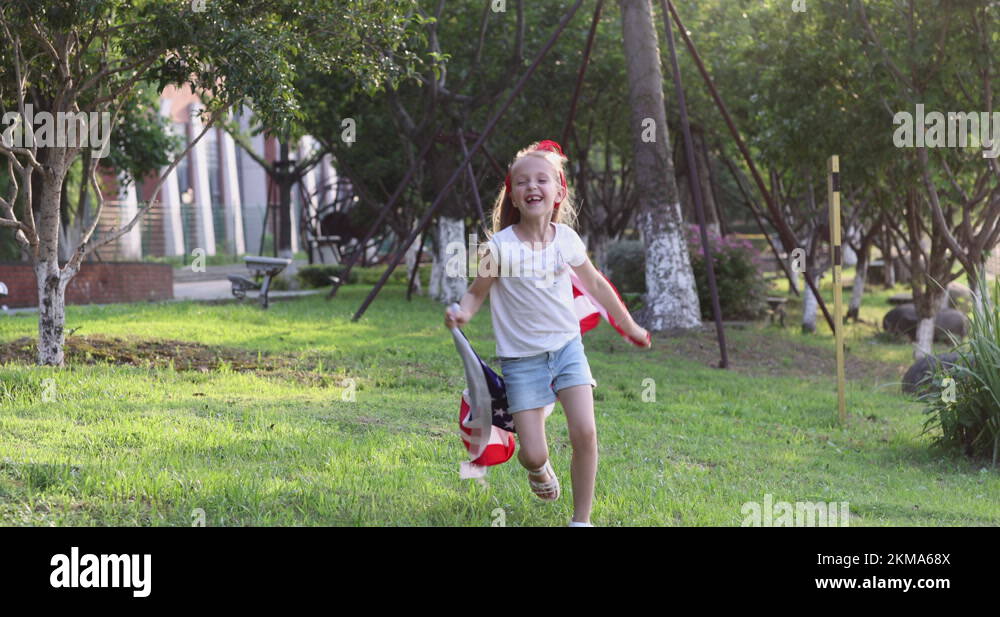 4k. Kid waving national USA flag outdoors. Cute Little Girl seven years ...