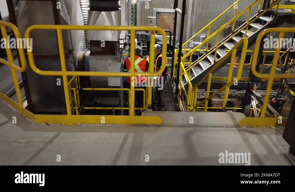 Two workers looking down with their mask and hard hats on, push in shot ...