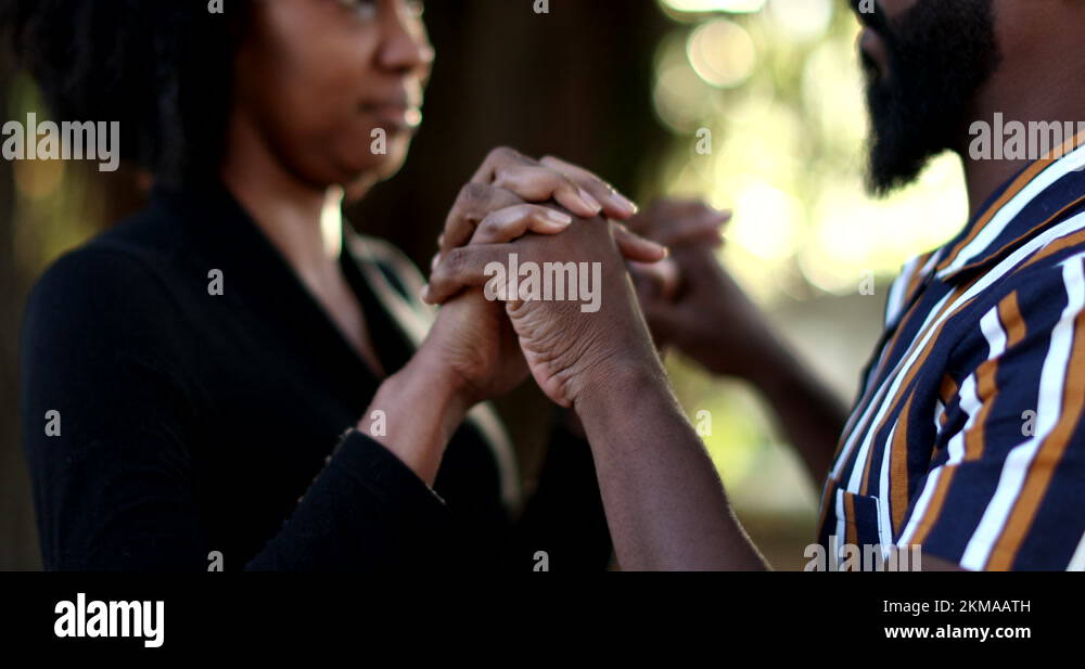 African couple holding hands and kissing outside with sun-flare ...