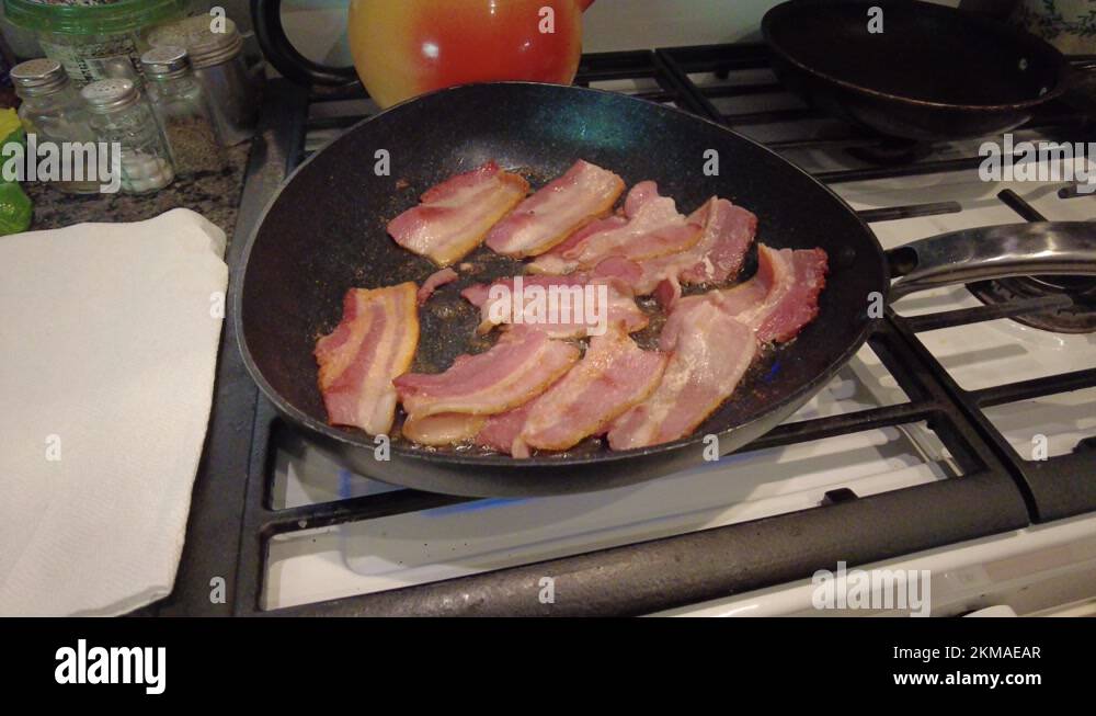 thick cut bacon sizzling in a hot skillet on a gas stove in grandma's ...