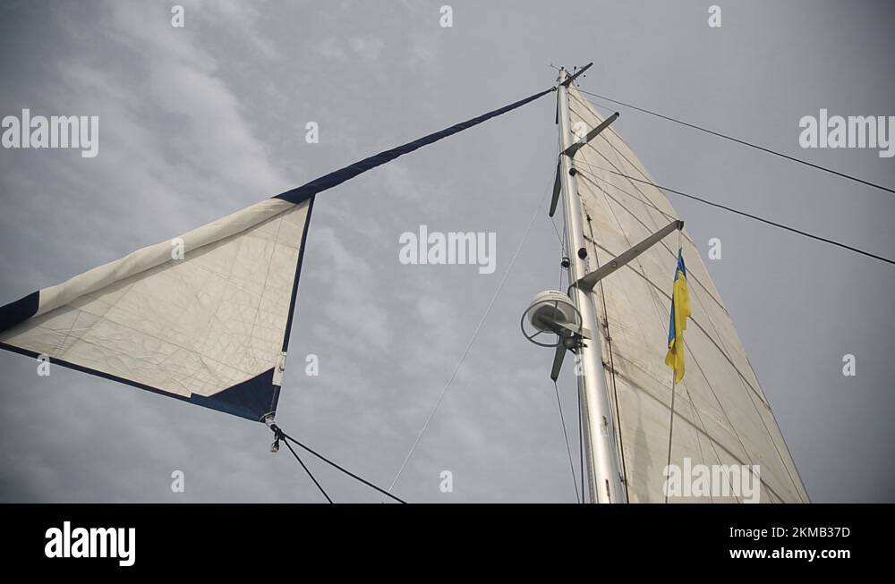 Ukrainian flag is flailing in the wind near the sail of a luxury yacht ...