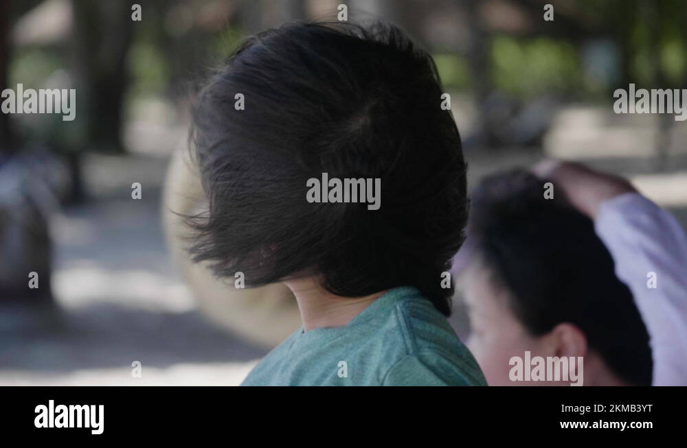 Asian 3 year old boy looking around at the beach with his mother as a ...