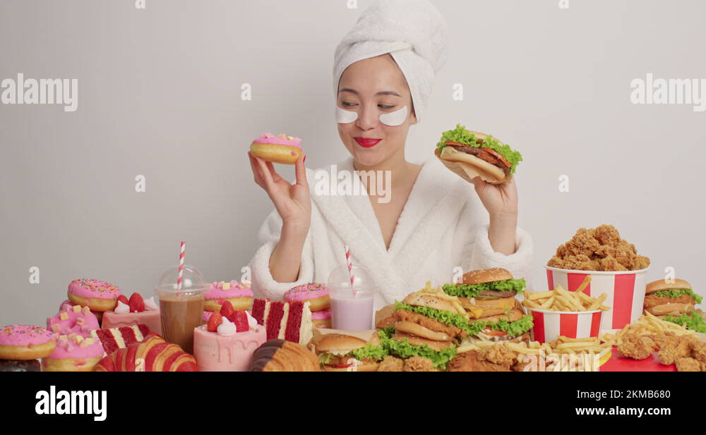Bad nutrition habits cheat meal. Pleased woman holds tasty doughnut and ...