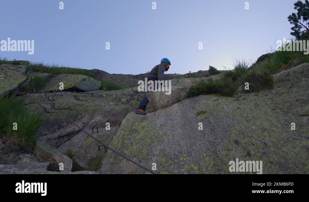 Man rock climber ascending via ferrata route on alpine terrain Stock ...