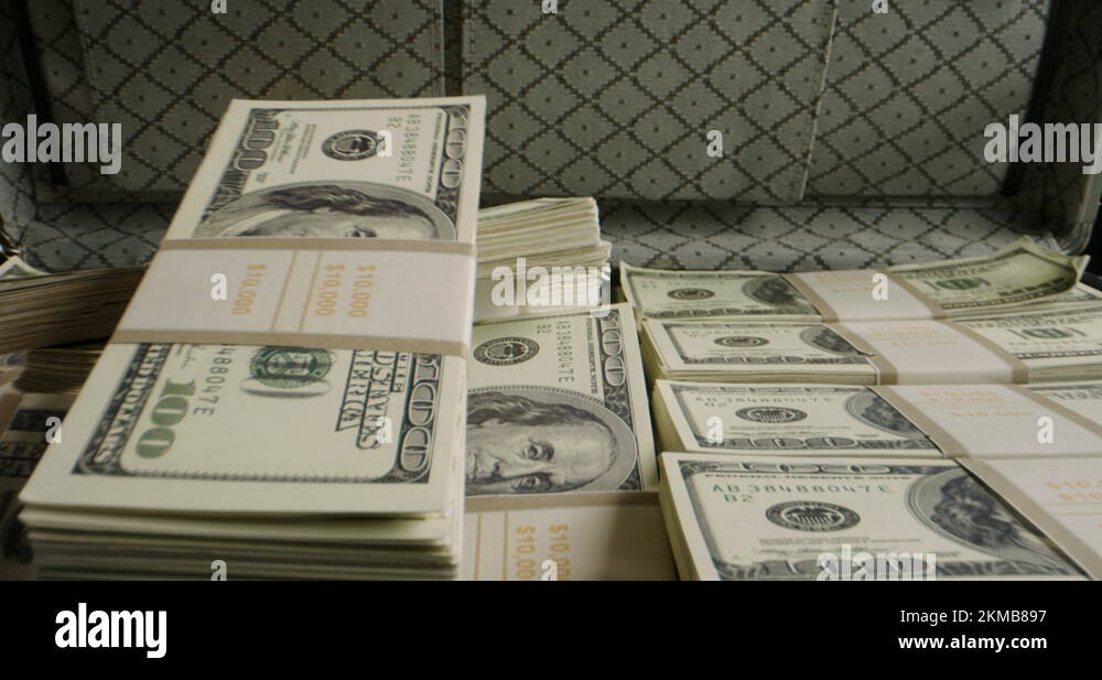 Packs of cash falling into a metal case filled with money. 100 dollar ...