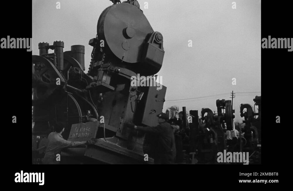 1940s: Men grabbing punch press hanging from chain, pushing and pulling ...