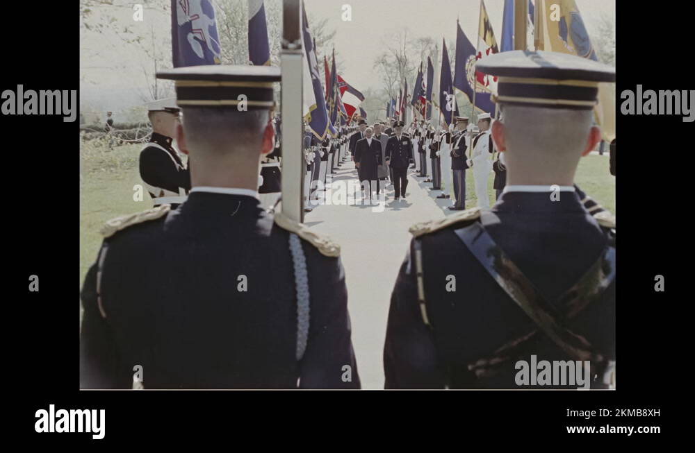 1960s: Group of men walk in between columns of men in uniform holding ...