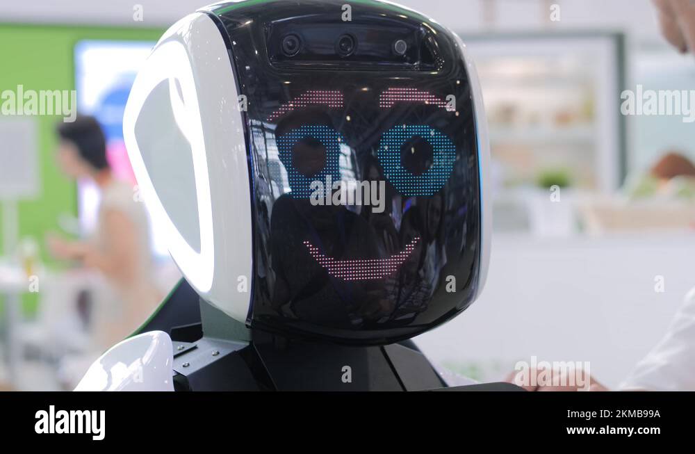 White cute robot with display face speaking with people at technology ...