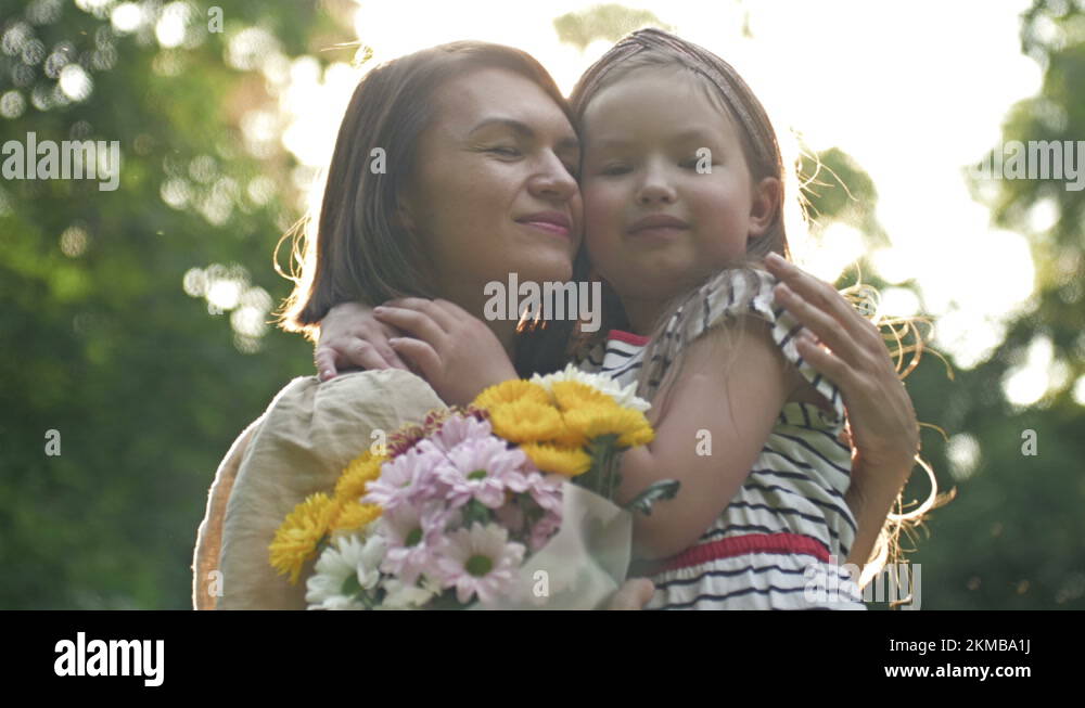 Little girl gives flowers to her mother. Lovely family together. Summer ...