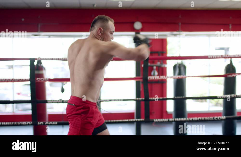 Muscular boxer is practising in the octagon cage. Shadow boxing Stock ...
