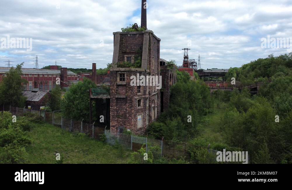 Abandoned old overgrown coal mine rusting wheel derelict building ...