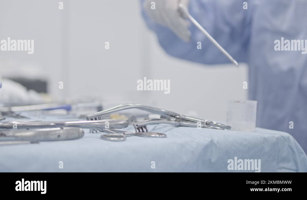 Surgery tools on a table in operating room. Doctors and nurse picking ...