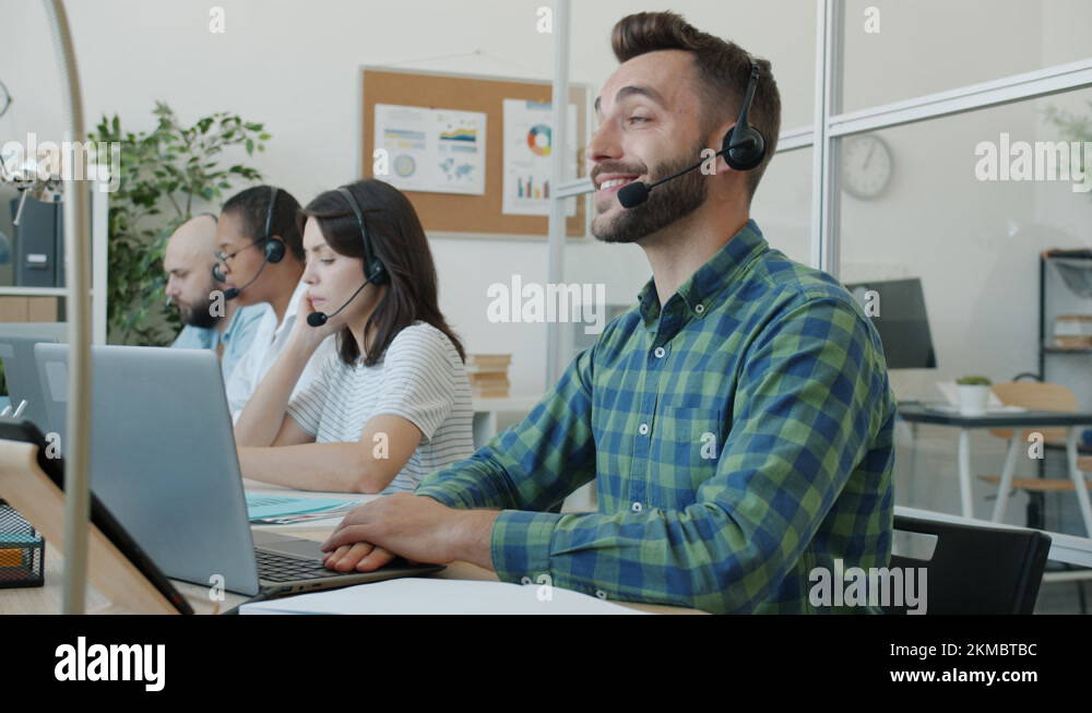 Tired guy working in call center talking then putting head on table ...