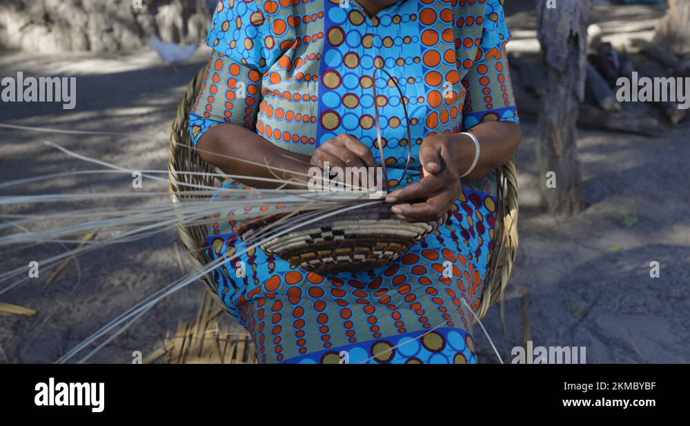 Close-up cropped view of a woman weaving traditional basket made from ...
