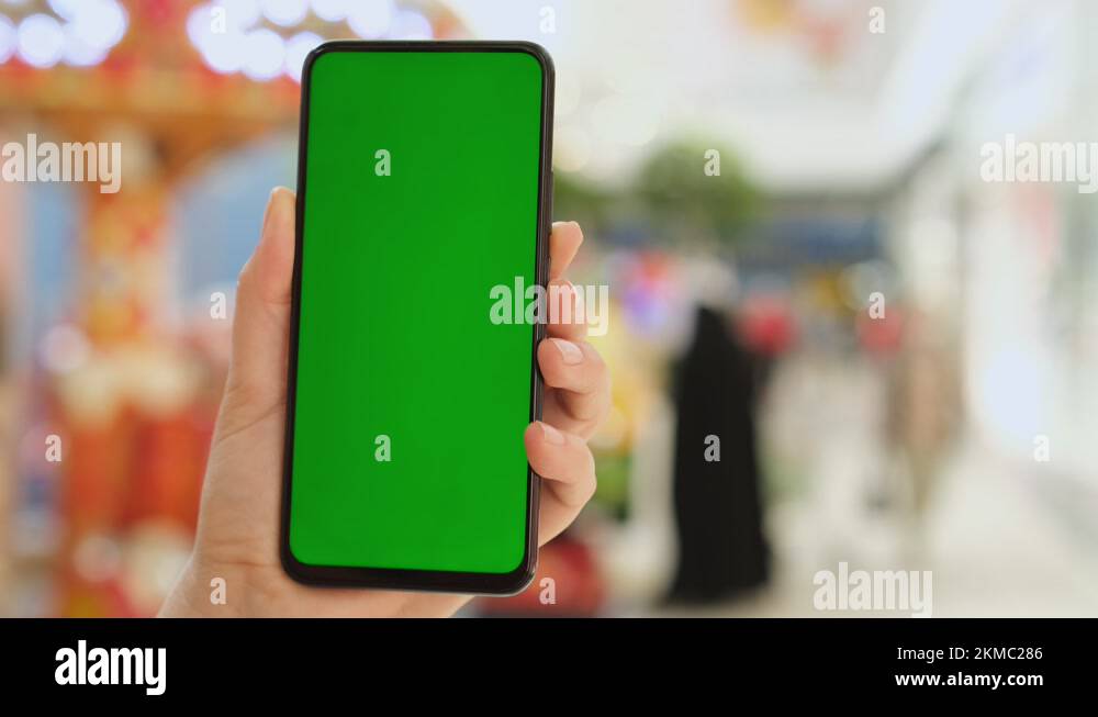 Back view of brunette holding chroma key green screen smartphone ...