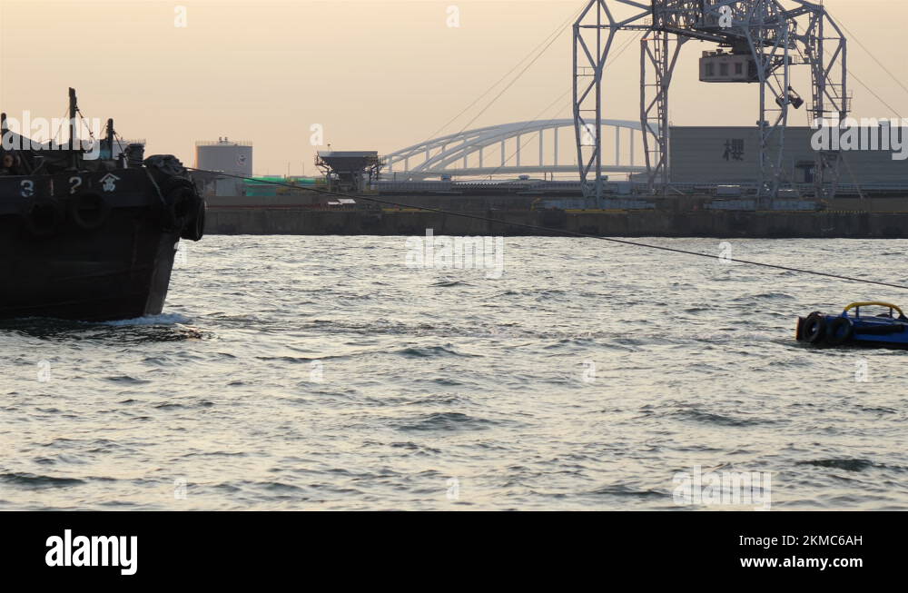 A small boat pulling out the big vessel on the back in Osaka Japan ...