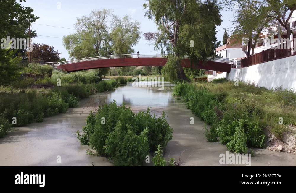 A small wooden bridge in a village. A woman pass through the bridge ...