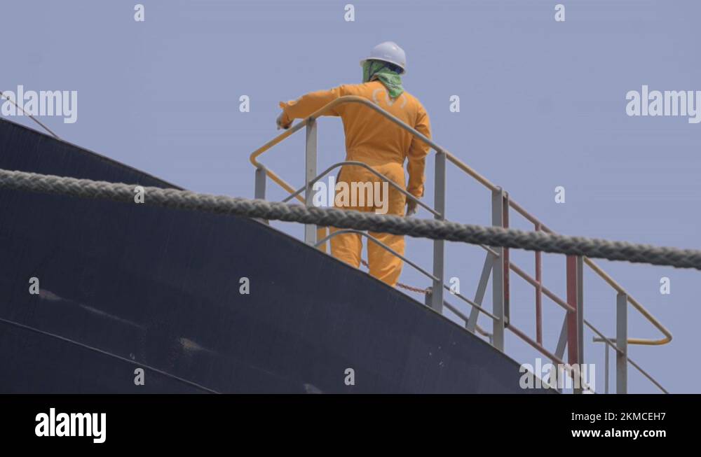 Seafarer At Work Gesturing On The Deck Of A Huge Cargo Vessel Under The ...