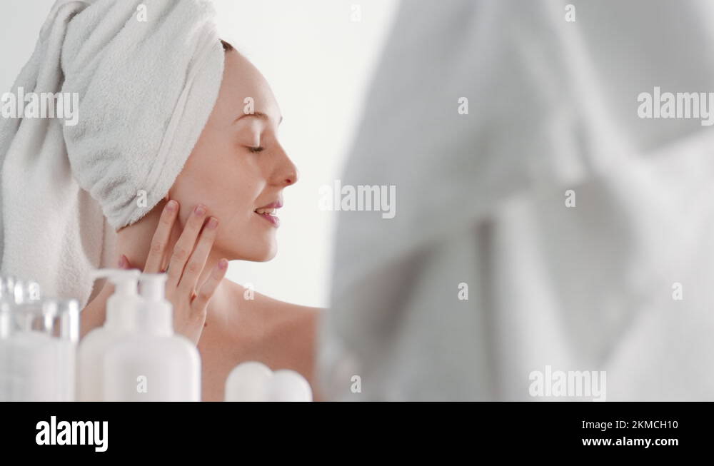 Slim young woman turns head and touches neck in front of mirror Stock ...